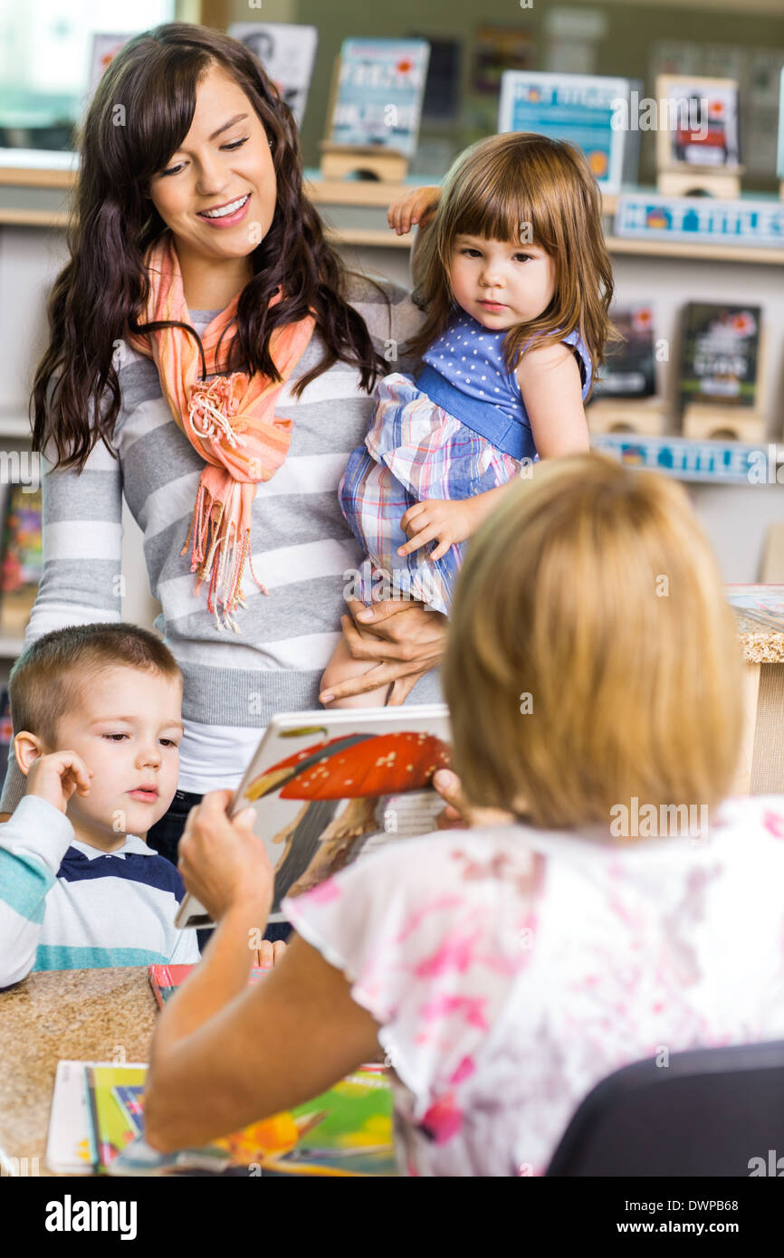 Family Looking At Librarian Showing Book Stock Photo - Alamy