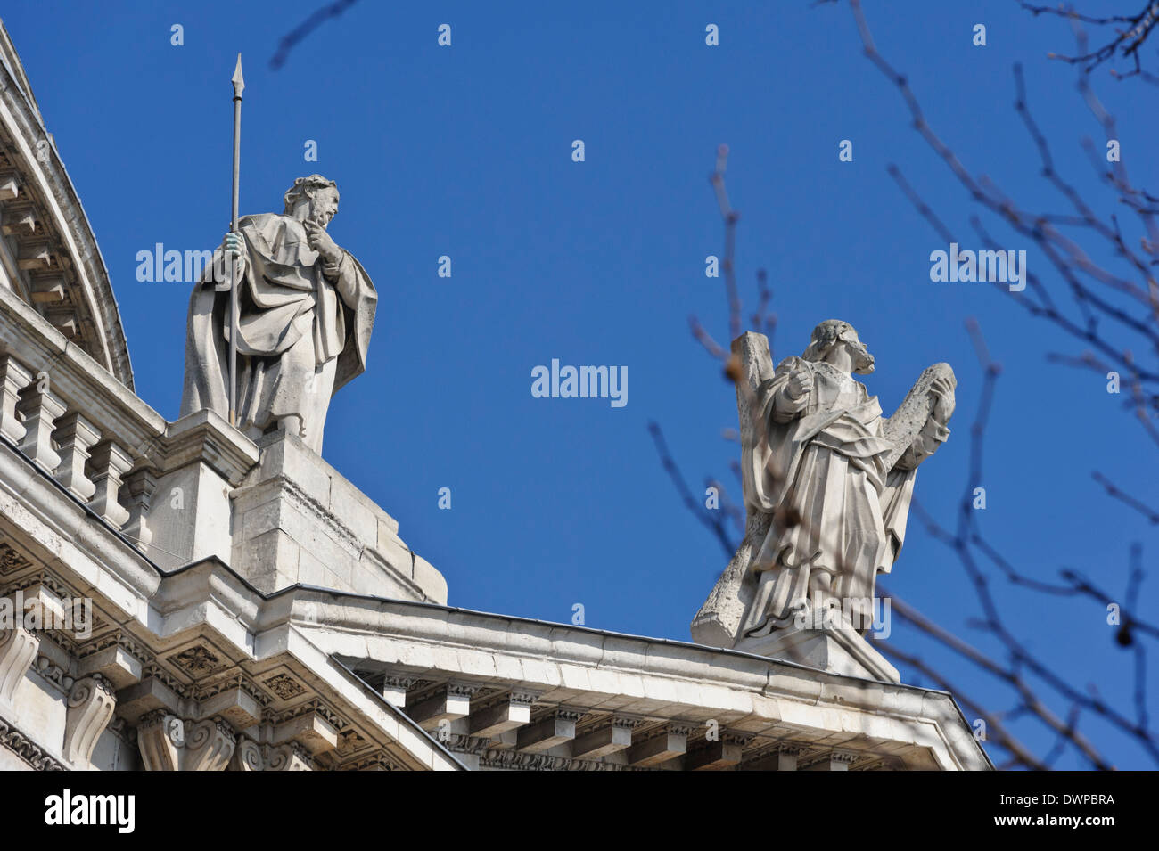 Two saints statues on the roof St Paul's Cathedral against a deep blue ...