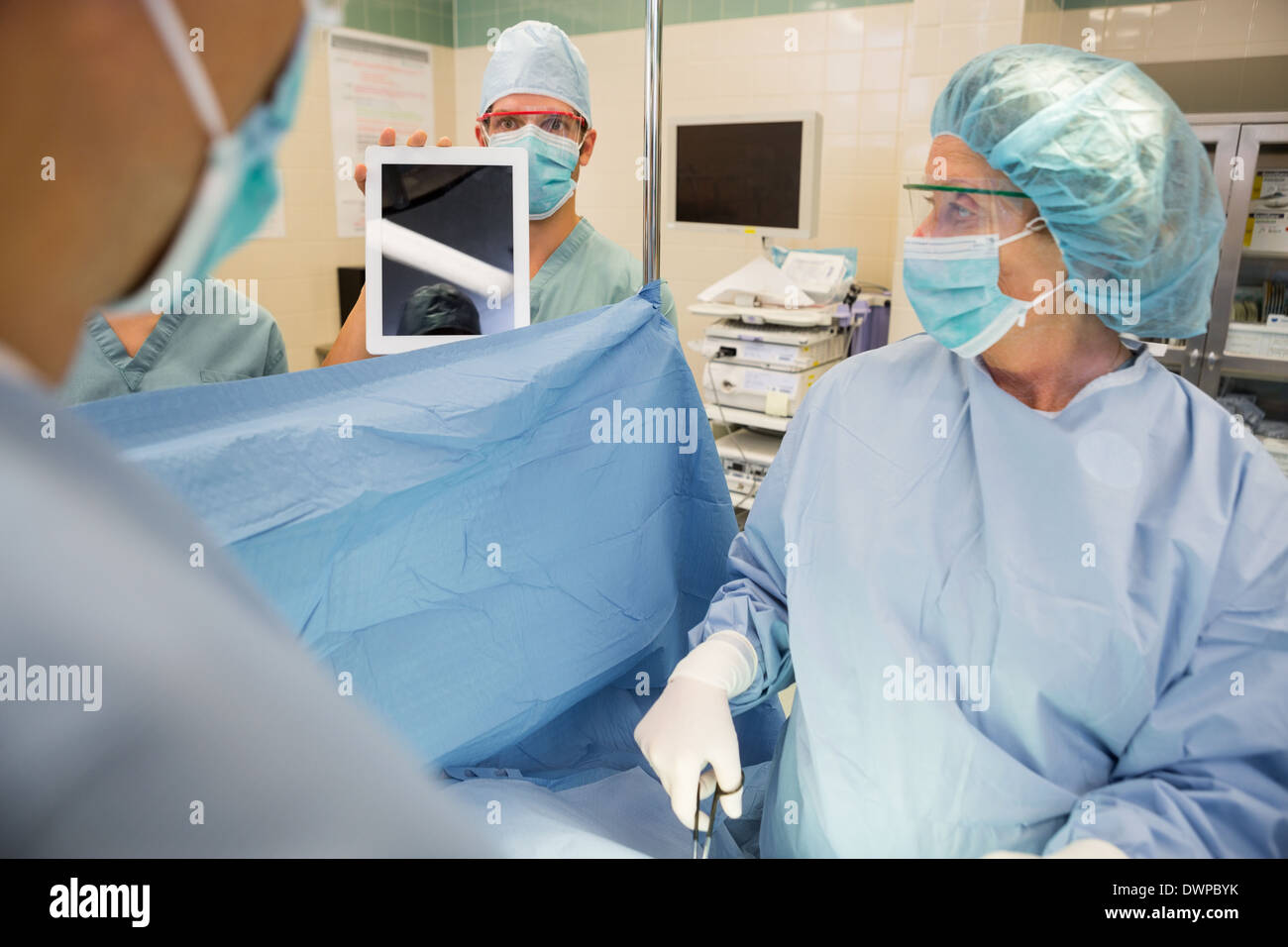 Nurse Showing Digital Tablet To Surgeons During Surgery Stock Photo - Alamy
