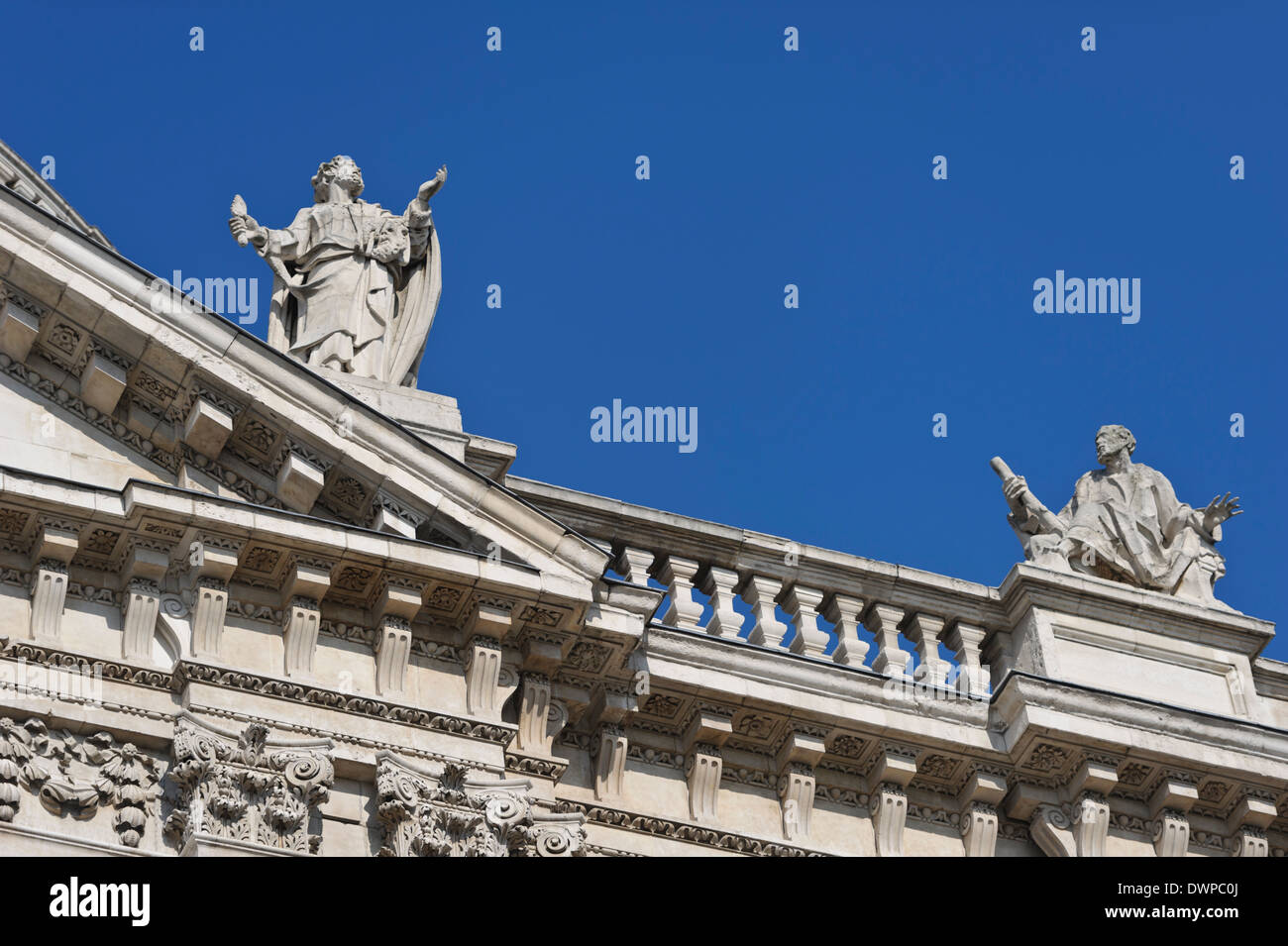 Two saints statues on the roof St Paul's Cathedral against a deep blue ...