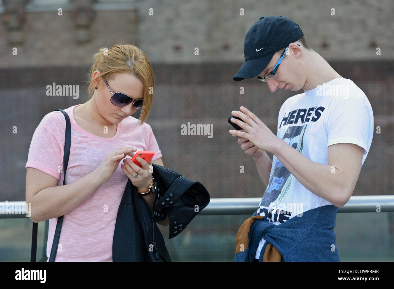 Two young persons busy texting in casual wear, London, England, United ...