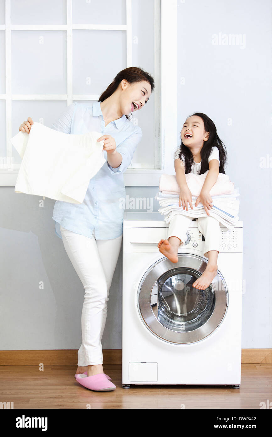 a woman and a daughter playing around washing machine Stock Photo - Alamy