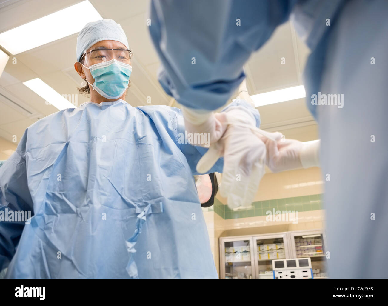 Nurse Assisting Doctor In Wearing Surgical Glove Stock Photo - Alamy