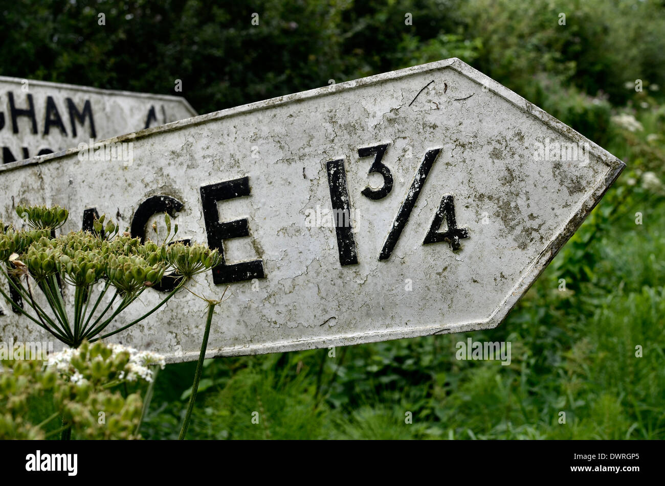 Typical rural / countryside direction signpost among undergrowth. 1 3/4 ...