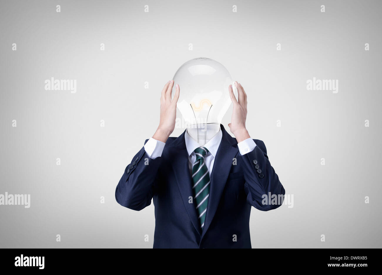 a man holding a light bulb in front of his face Stock Photo - Alamy