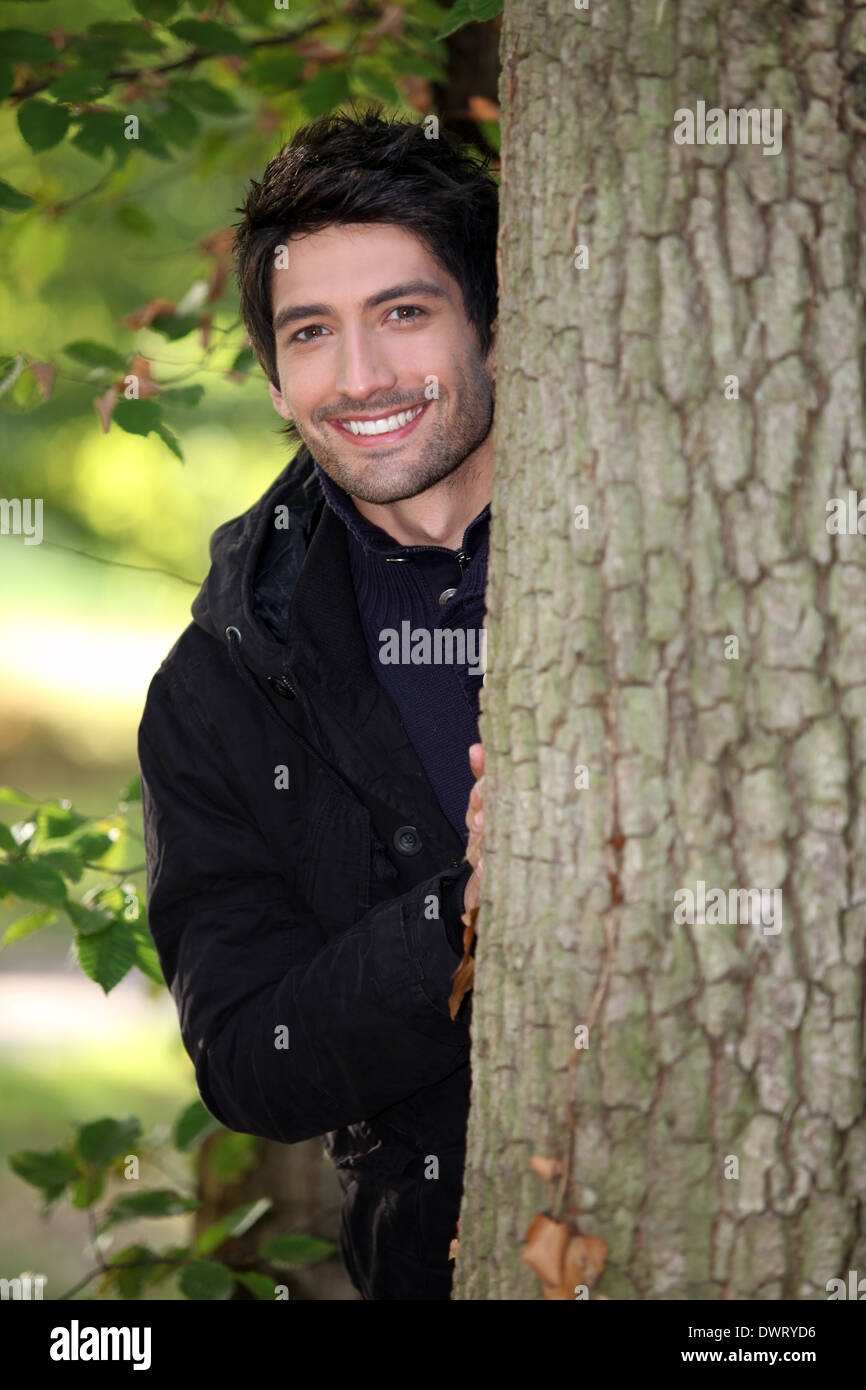 Man behind a tree trunk Stock Photo - Alamy