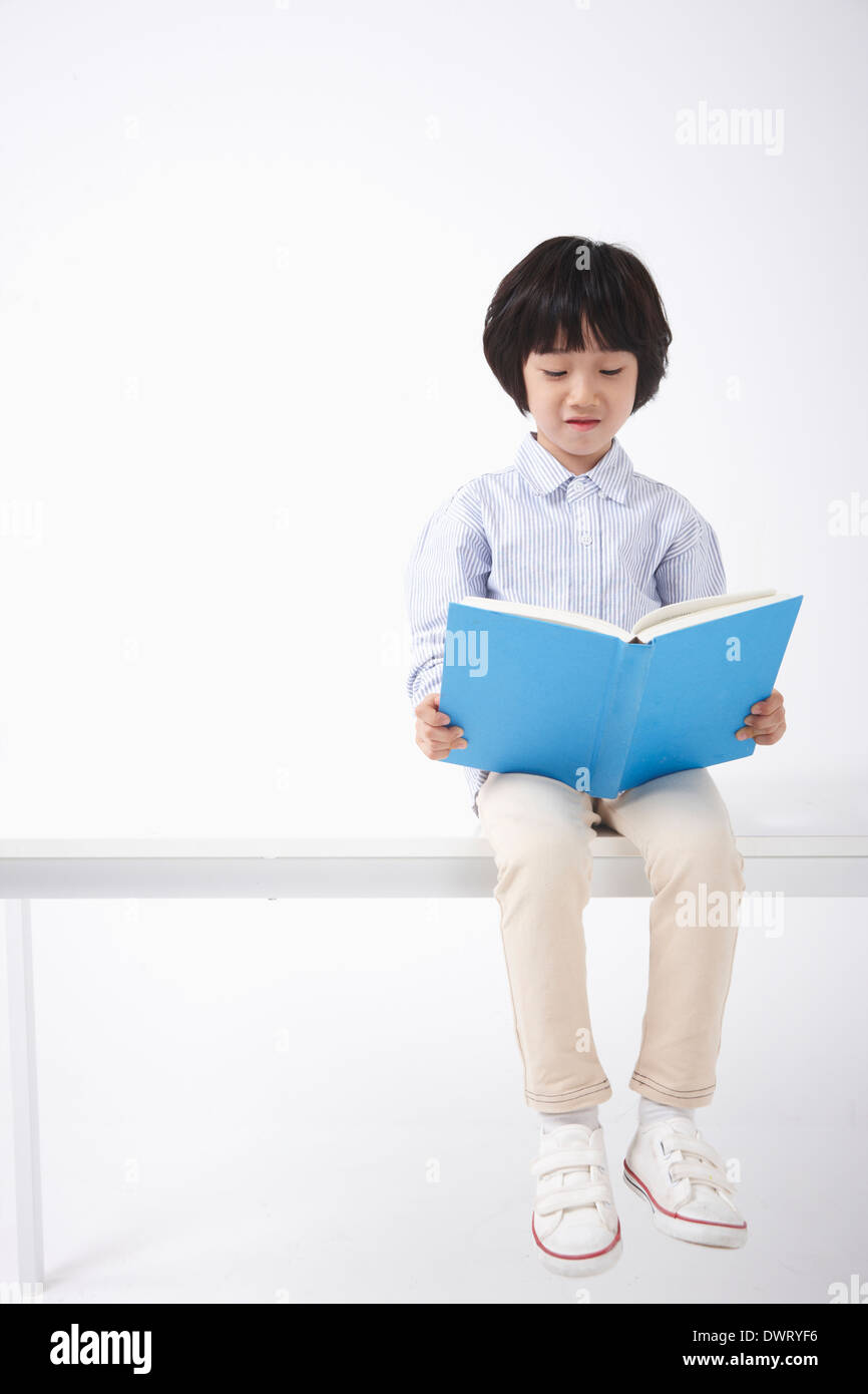 a kid sitting on a table reading a book Stock Photo - Alamy