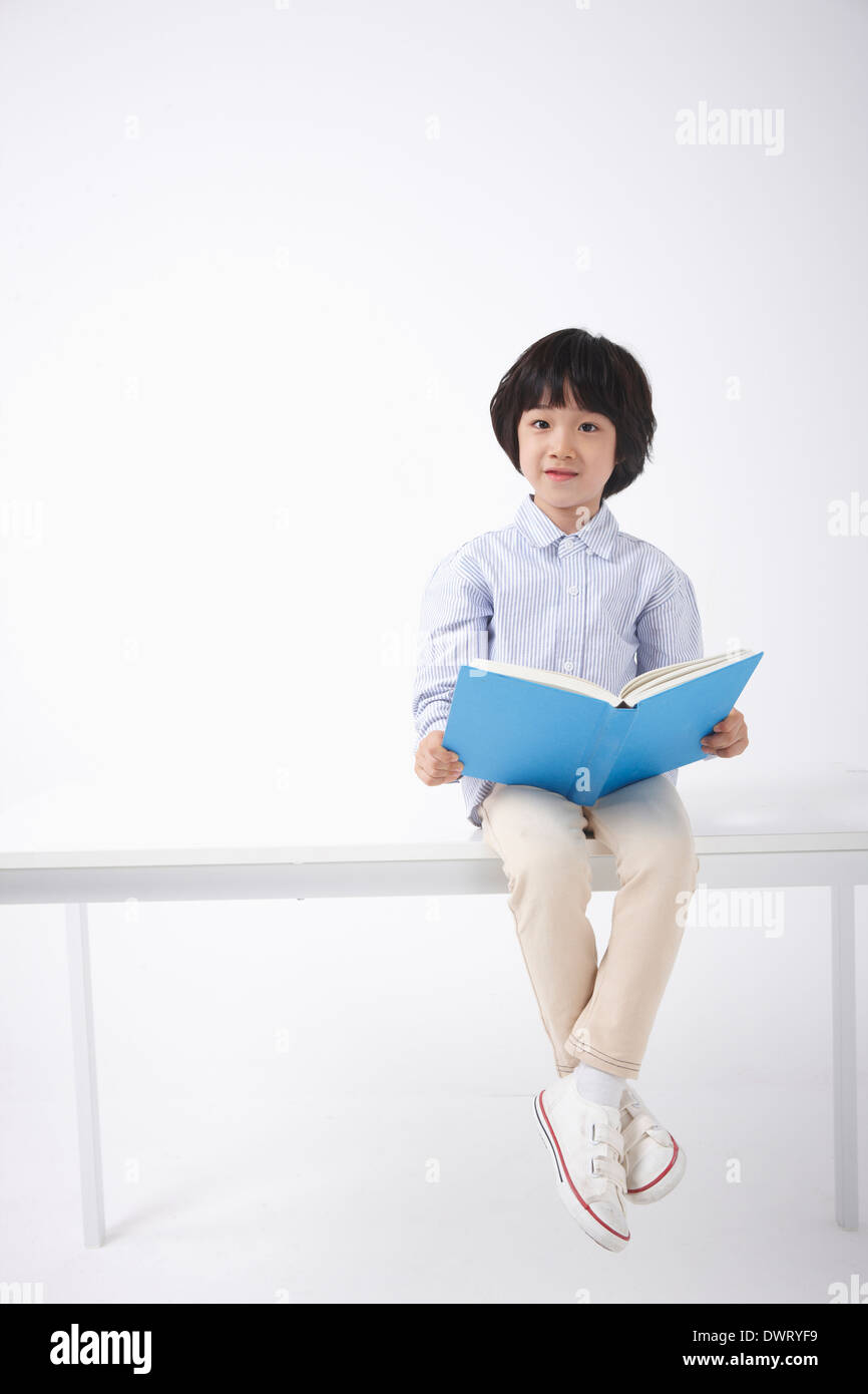 a kid sitting on a table reading a book Stock Photo - Alamy