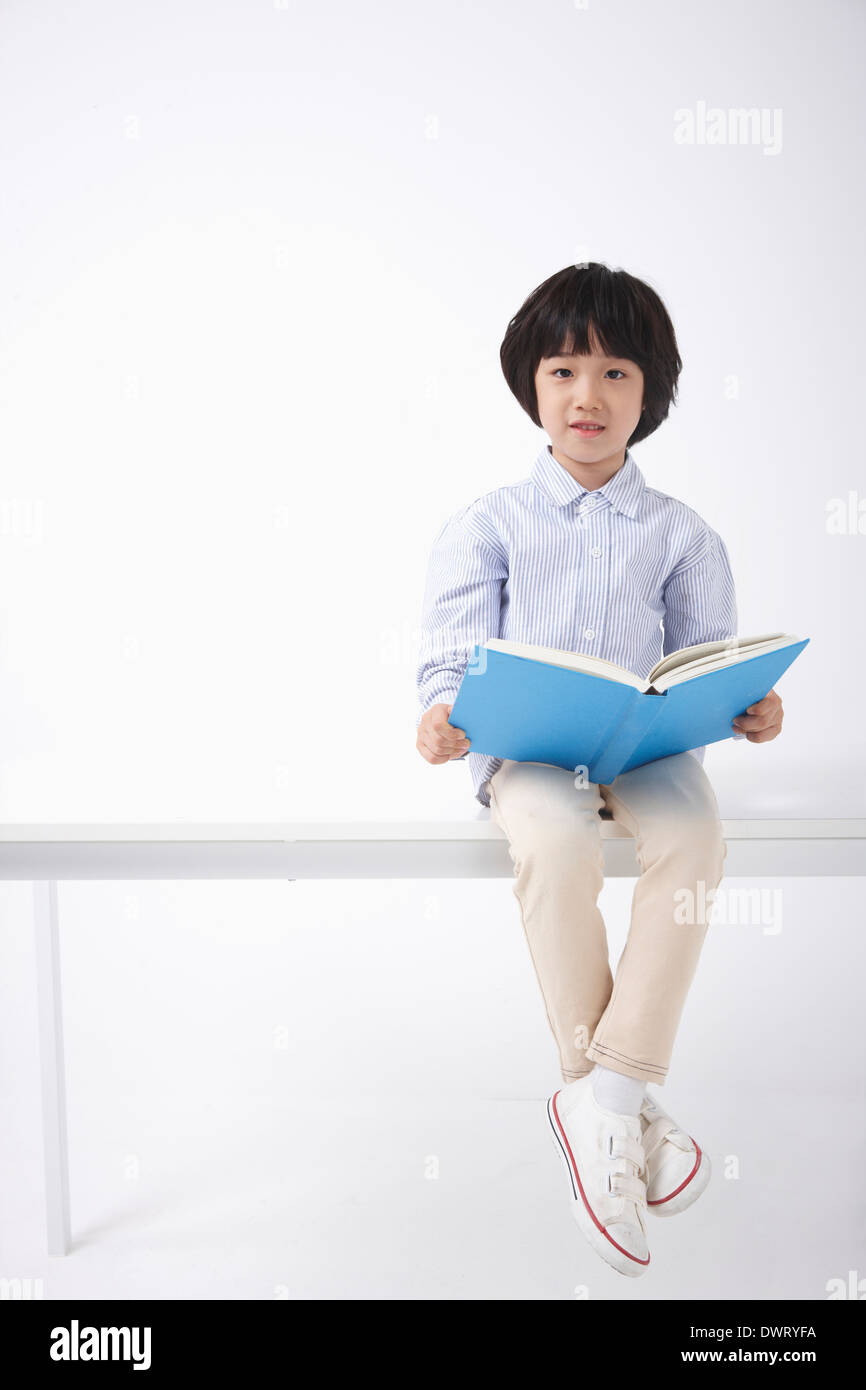 a kid sitting on a table reading a book Stock Photo - Alamy