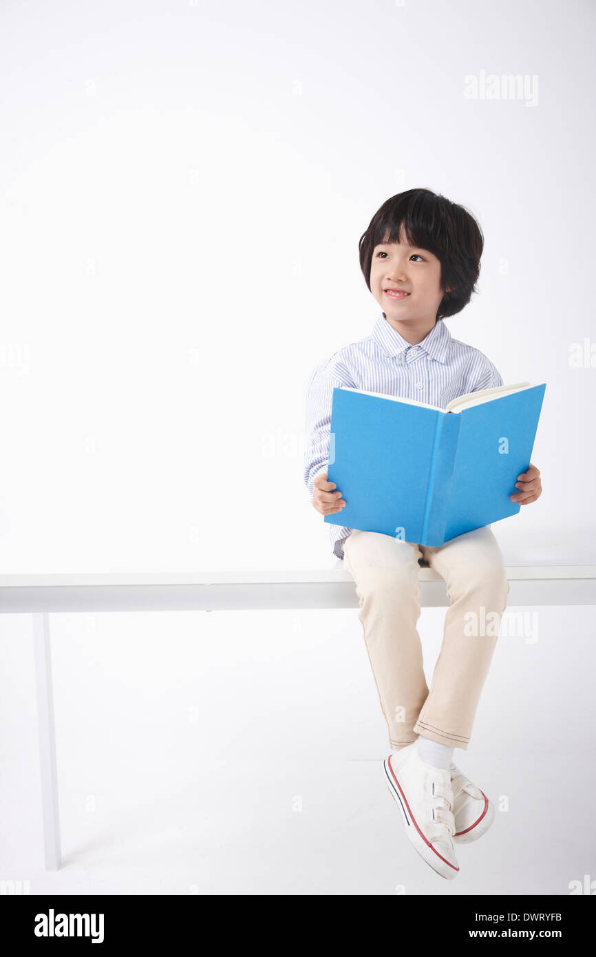 a kid sitting on a table reading a book Stock Photo - Alamy