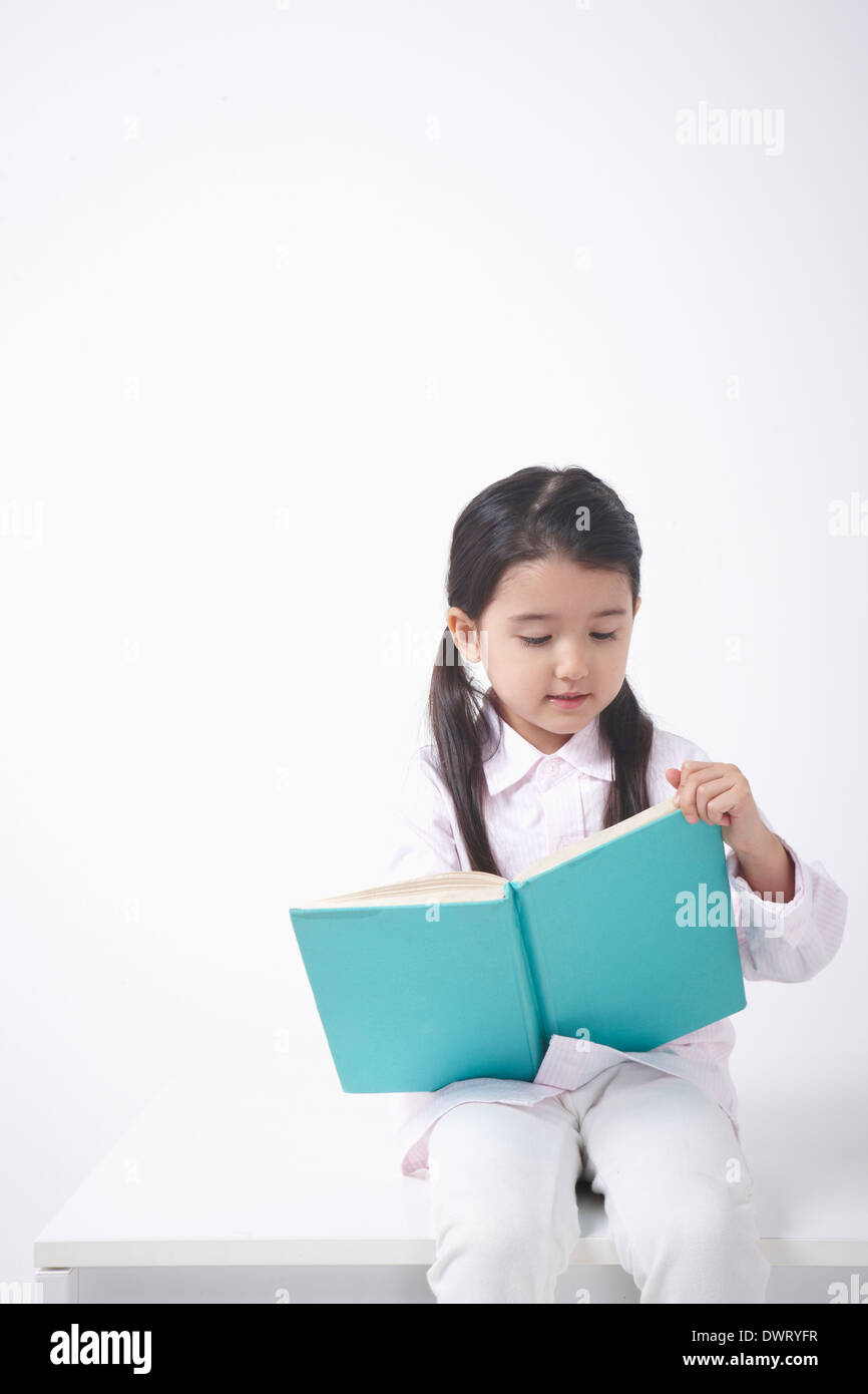 a kid sitting on a table reading a book Stock Photo - Alamy
