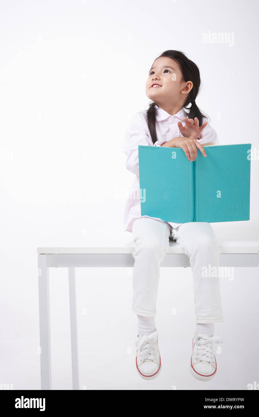 a kid sitting on a table reading a book Stock Photo - Alamy