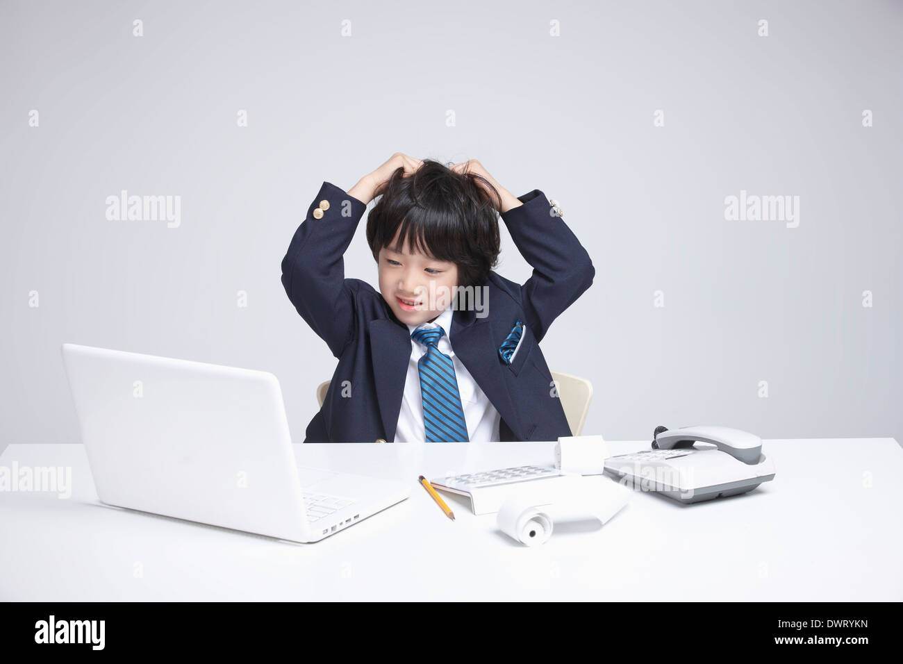 a kid wearing a business suit looking stressed while using computer ...