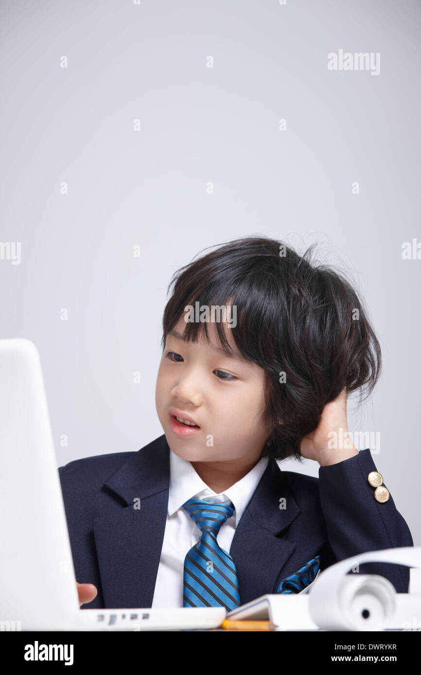 a kid wearing a business suit looking stressed while using computer ...