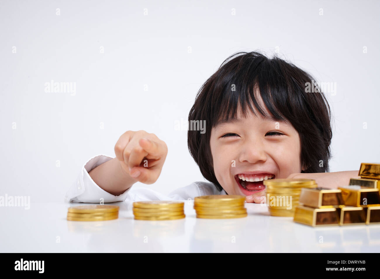 a kid wearing a business suit with coins and gold bars Stock Photo - Alamy