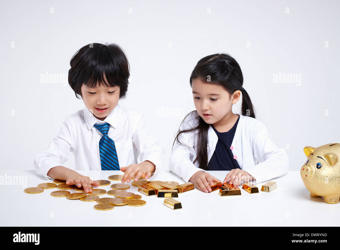 kids wearing business clothes at a table with coins and gold bars Stock ...