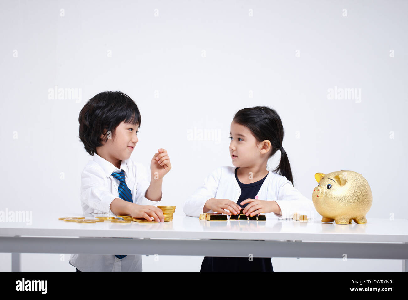 kids wearing business clothes at a table with coins and gold bars Stock ...