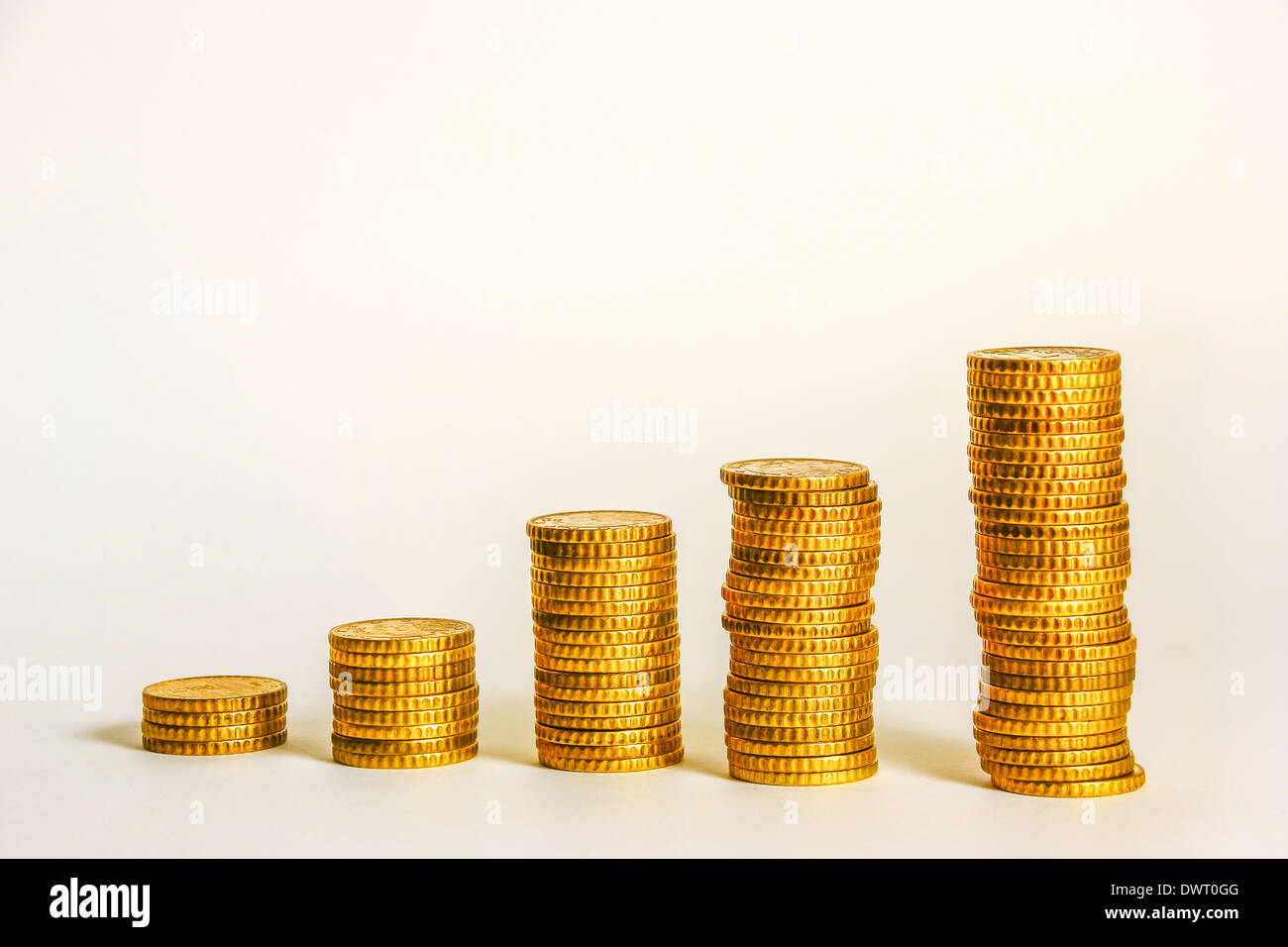 Yellow coins lined up from short to tall stacks with white background ...