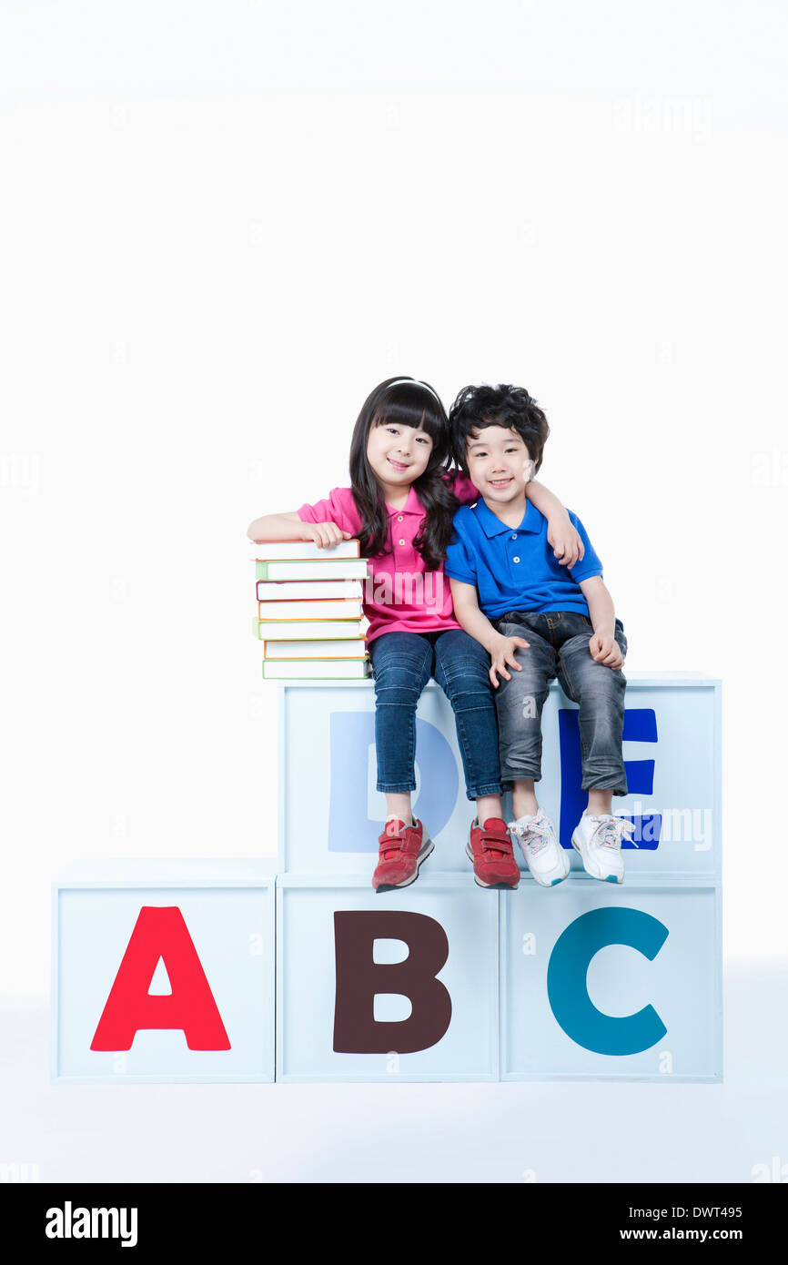 kids sitting on alphabet blocks with books Stock Photo - Alamy