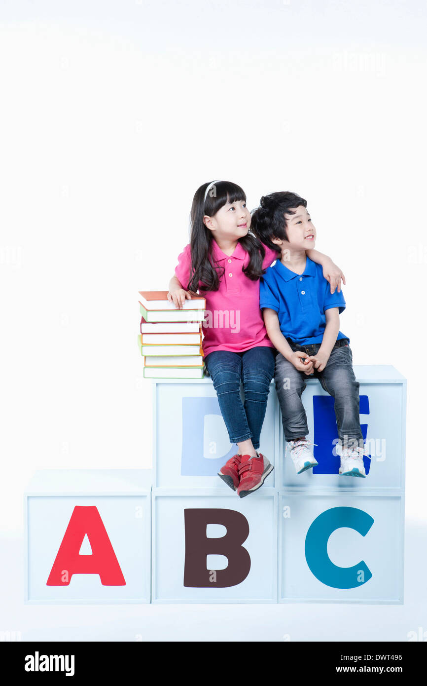 kids sitting on alphabet blocks with books Stock Photo - Alamy