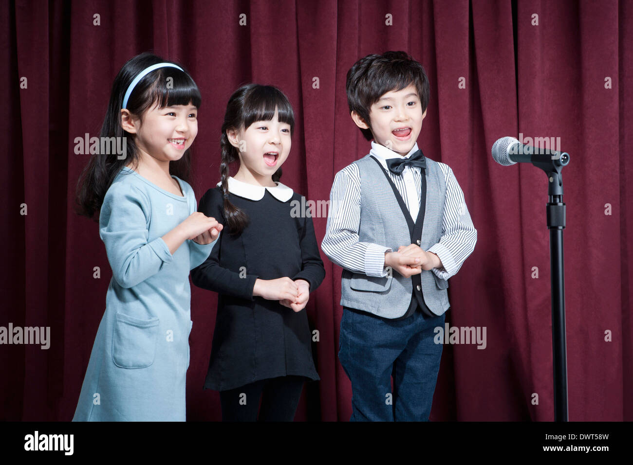 three children performing on stage Stock Photo - Alamy