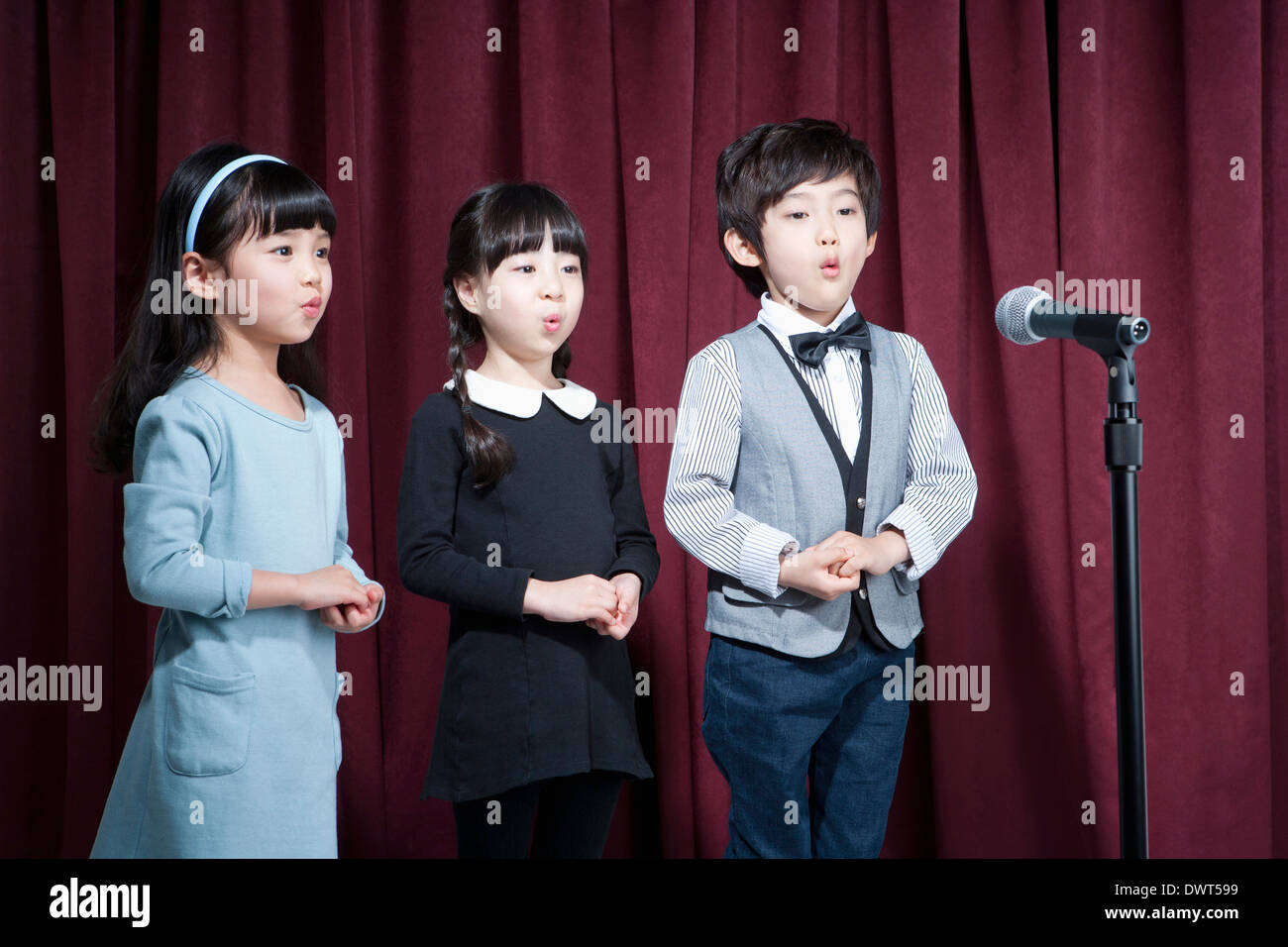three children performing on stage Stock Photo - Alamy