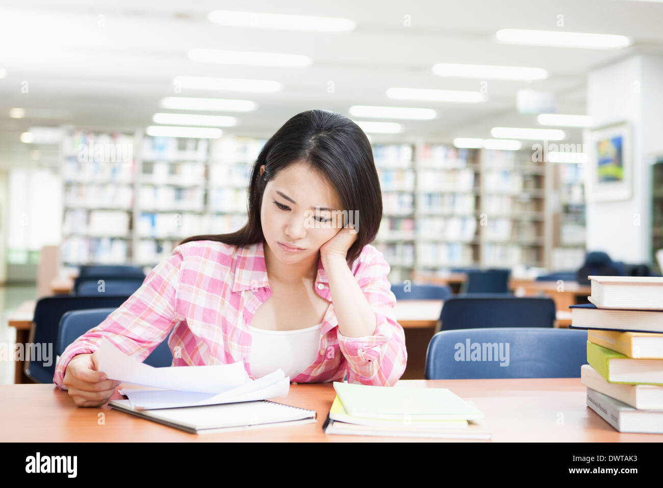 a girl sitting in the library studying Stock Photo - Alamy