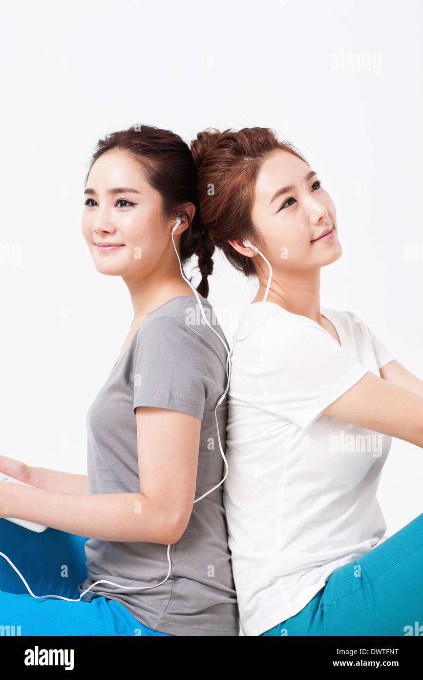 two women sitting on the floor listening to music Stock Photo - Alamy