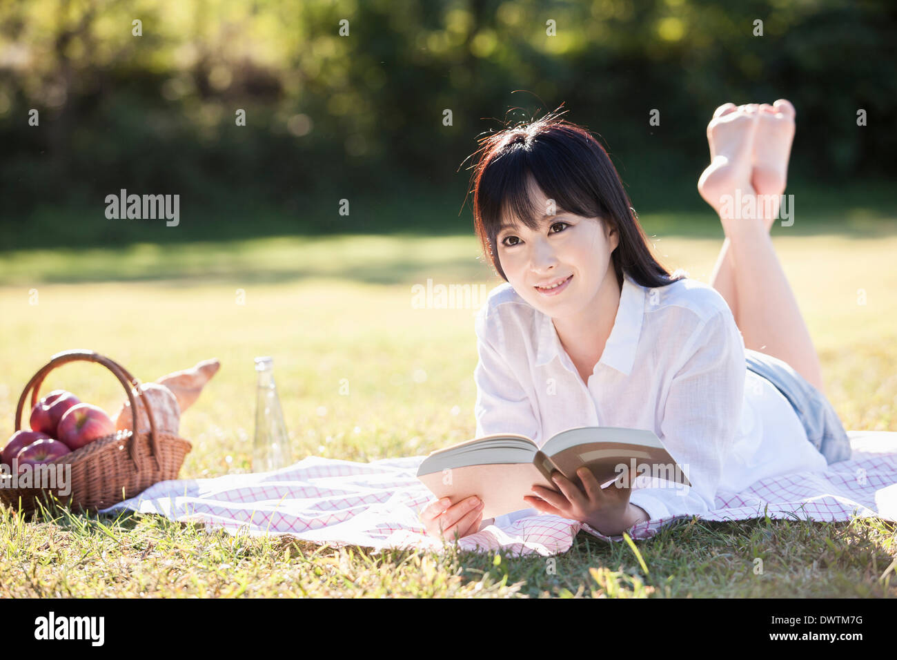 a woman reading a book on the grass Stock Photo - Alamy