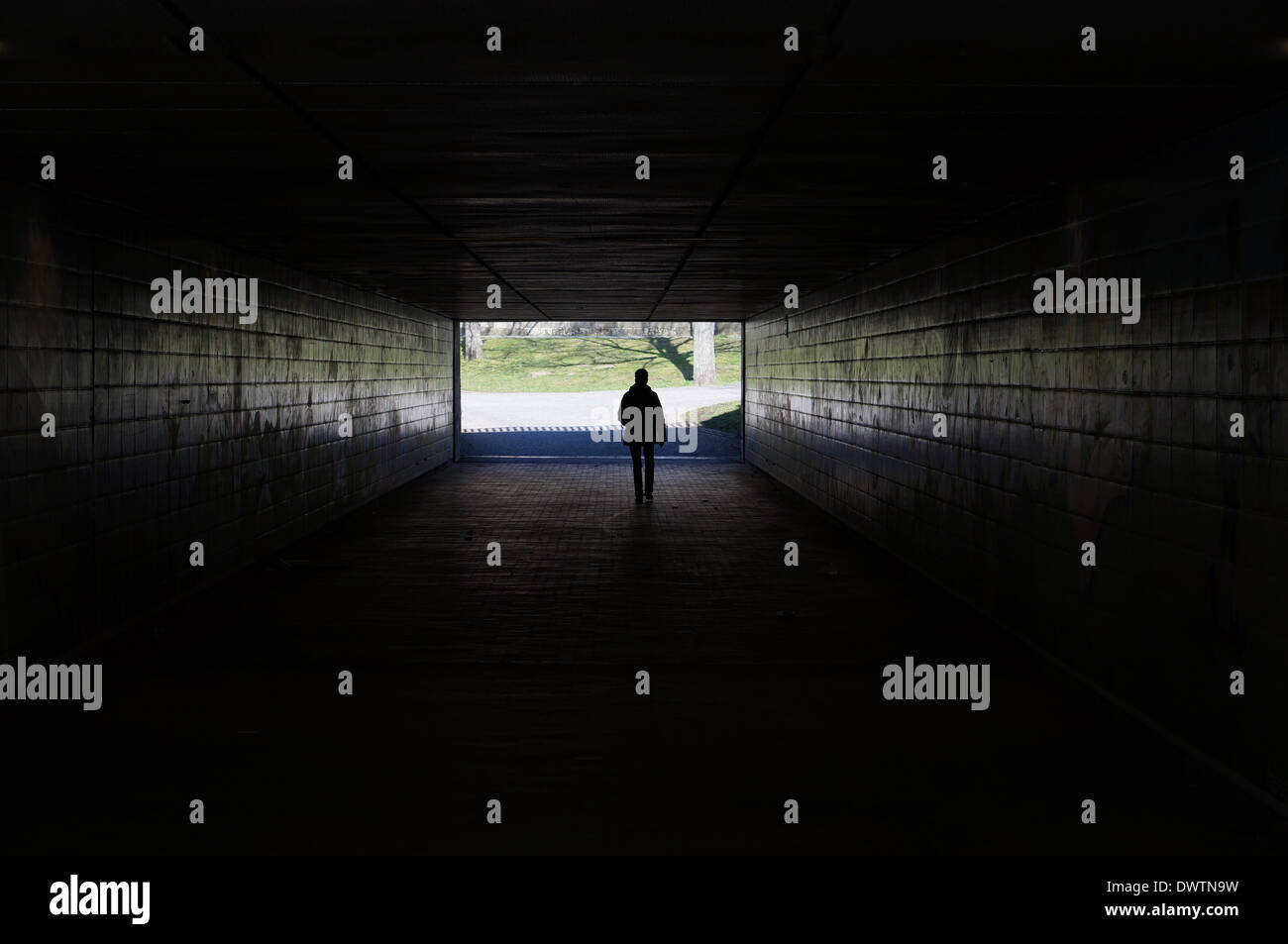 silhouette of a person walking through a dark underpass symbolizing ...