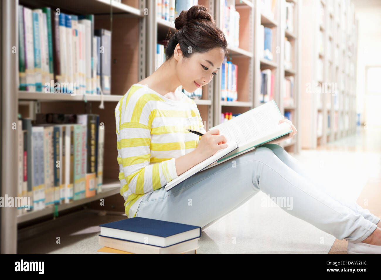 a girl sitting in the library studying Stock Photo - Alamy