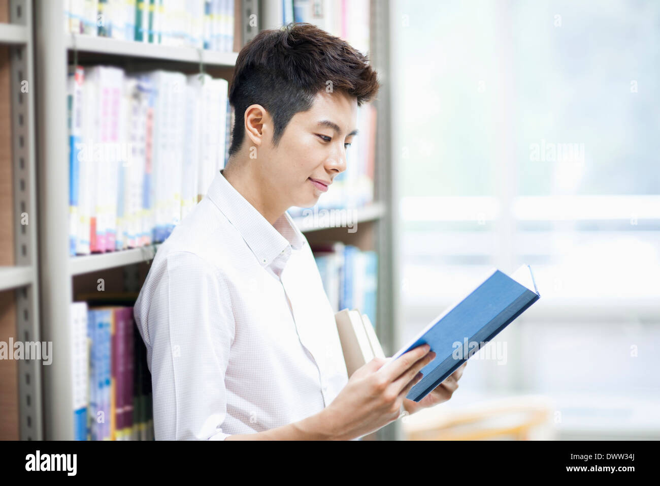 a boy reading a book in the library Stock Photo - Alamy