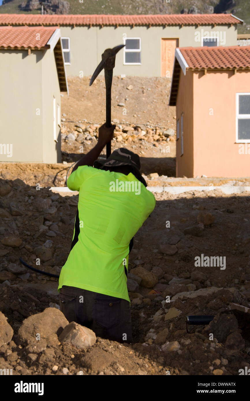 A worker digging trenches for electrical cables at Kleinmond's low cost ...