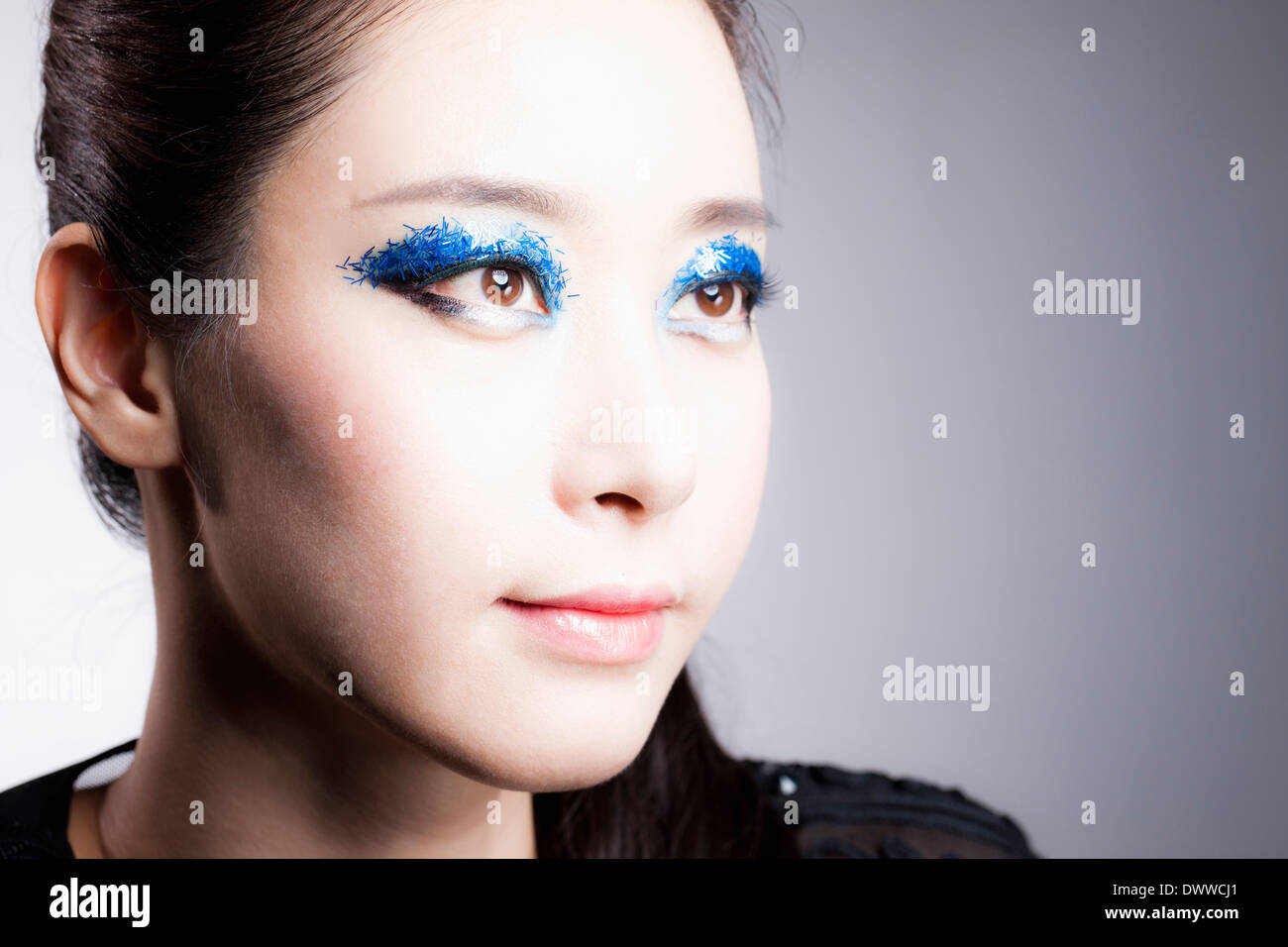 a woman with a black dress and heavy blue make up Stock Photo - Alamy