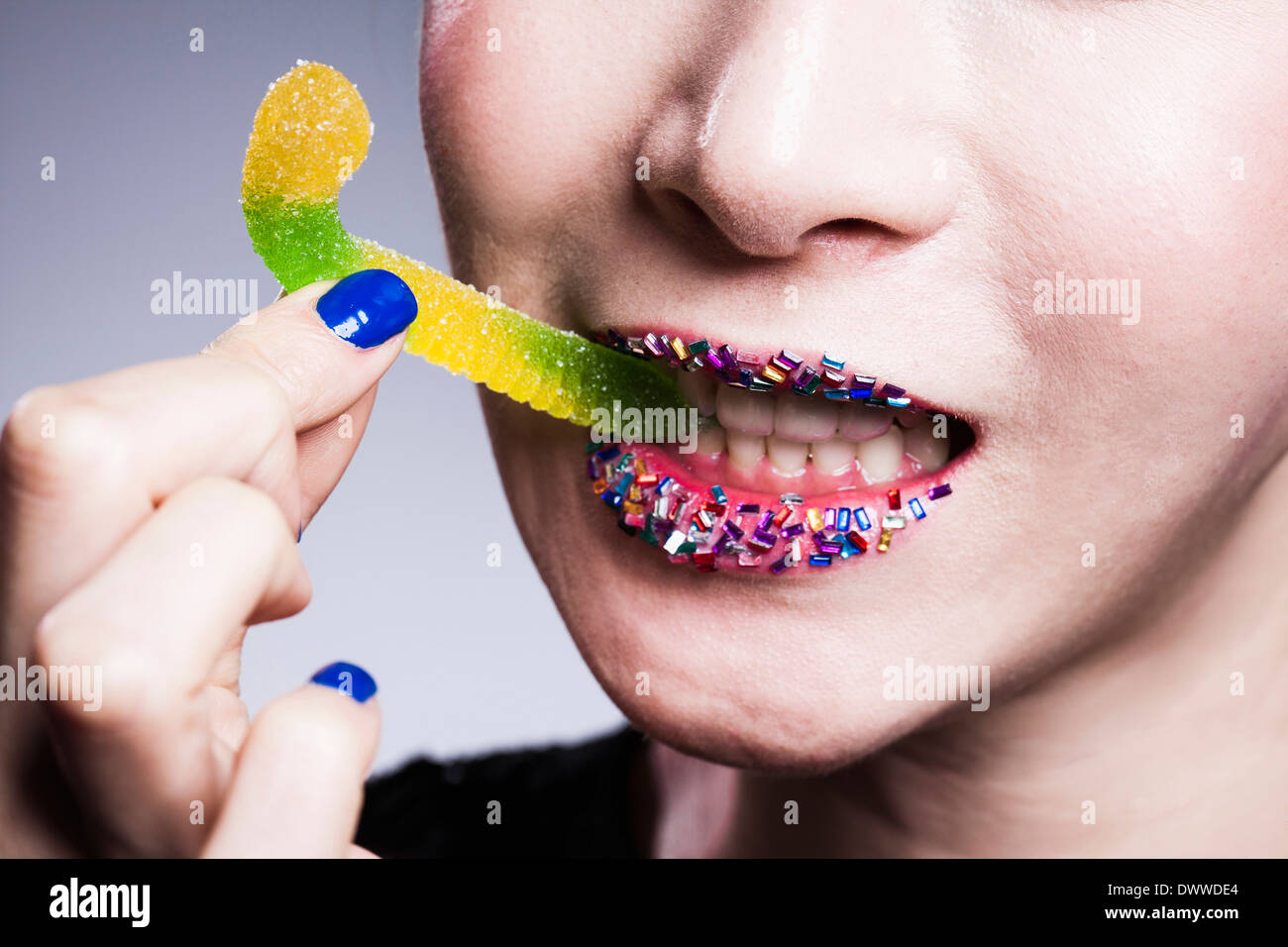 a woman with colorful lips eating candy Stock Photo - Alamy