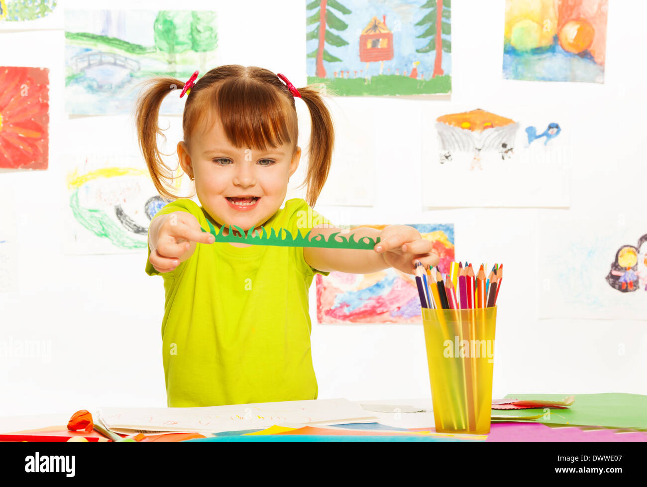 Cute little girl cutting and gluing color paper in the preschool art ...