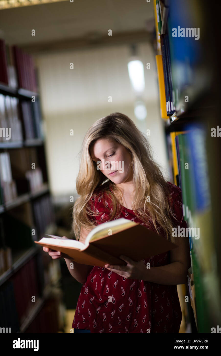 A young blonde haired woman undergraduate student studying reading ...
