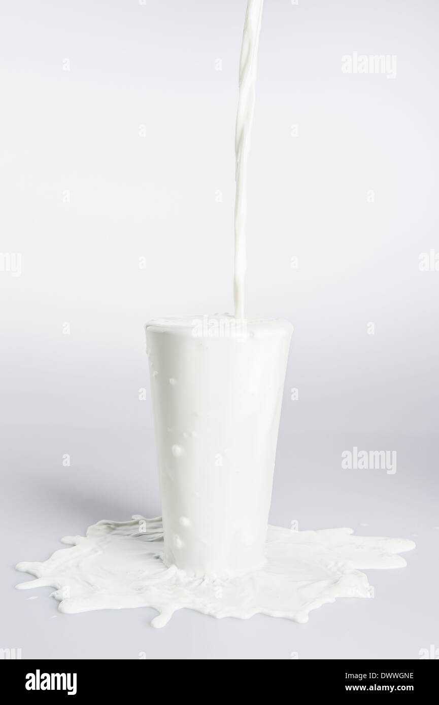 milk being poured in a glass so it spills Stock Photo - Alamy