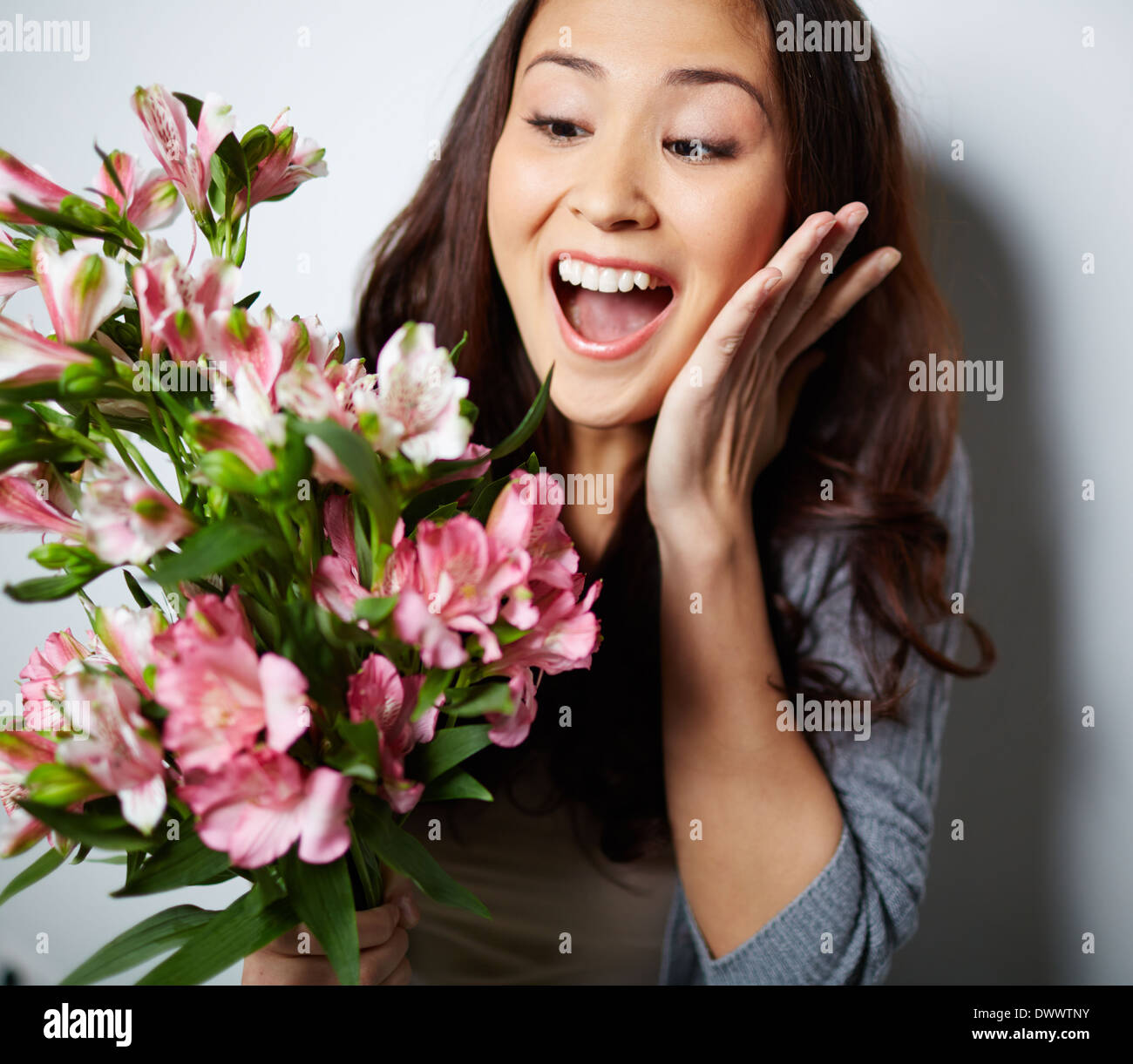 Portrait of ecstatic woman with bunch of flowers looking at it ...