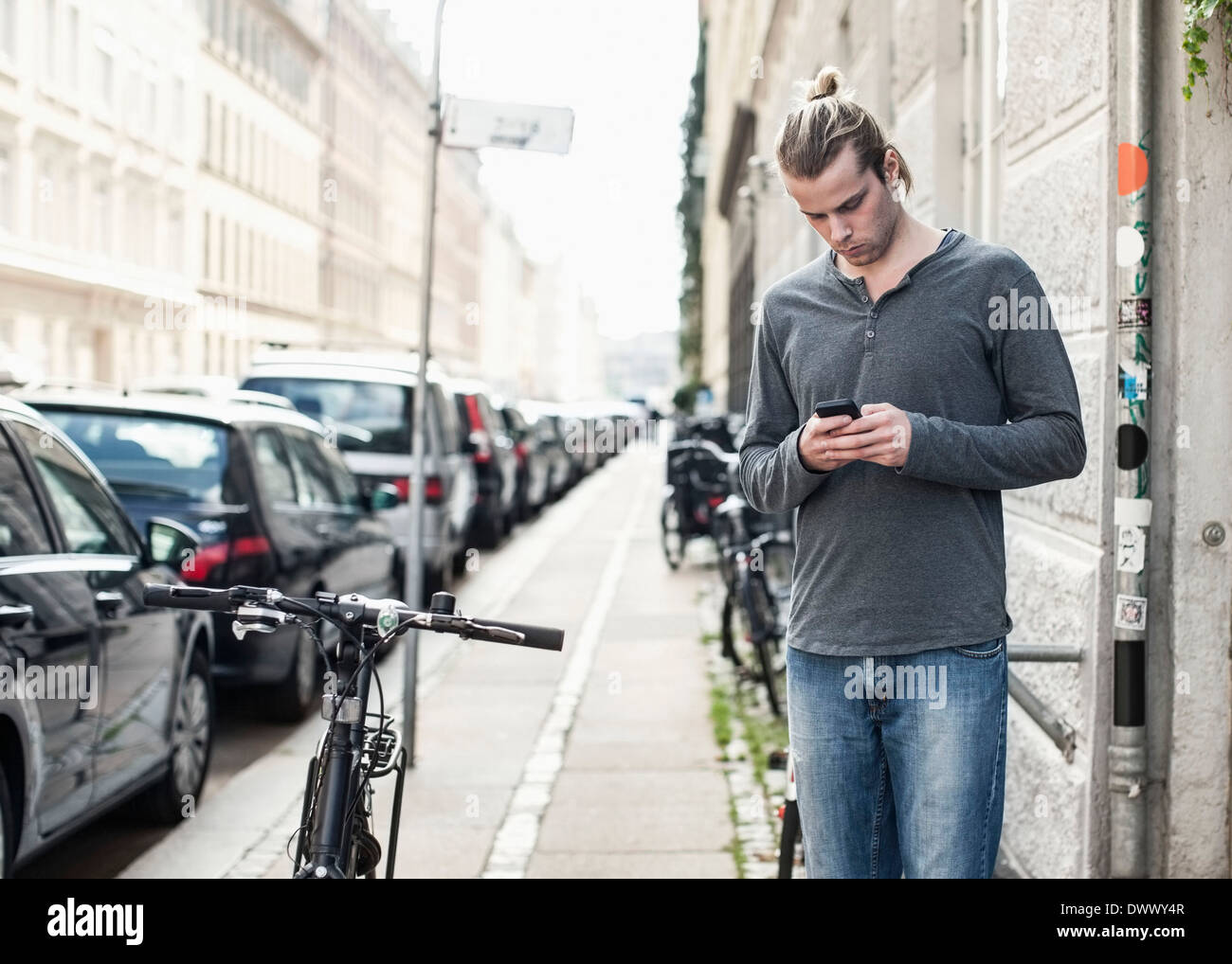 Young man text messaging through mobile phone while standing on ...