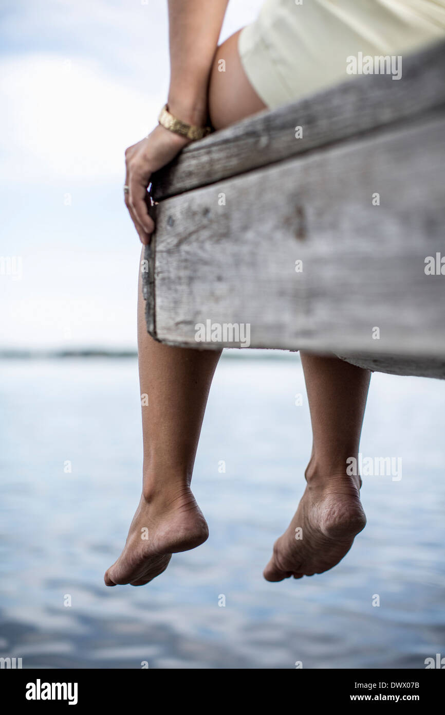 Low section of woman dangling feet from pier Stock Photo - Alamy