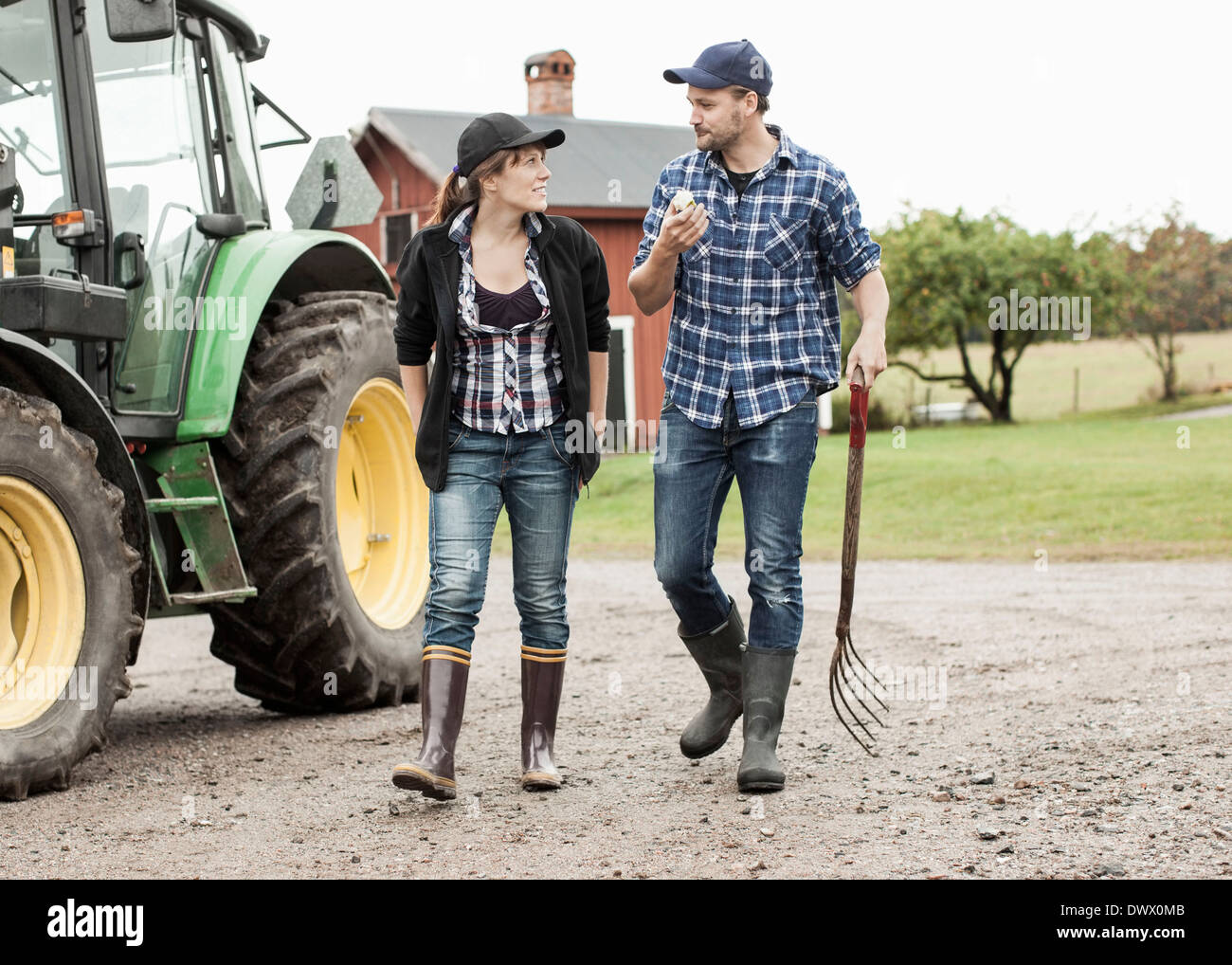 Full length of farming couple walking by tractor Stock Photo - Alamy