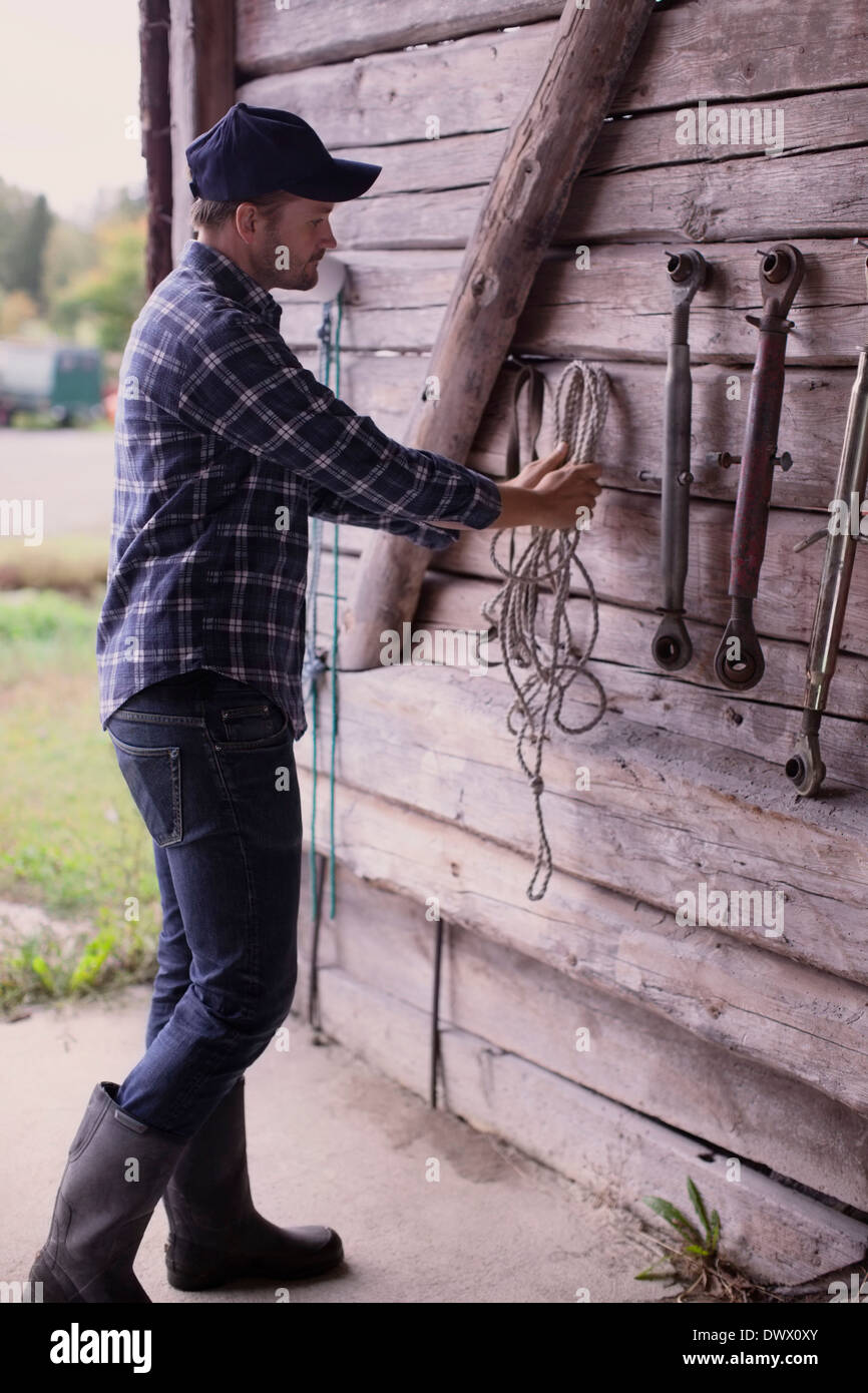 Full length of farmer arranging rope in barn Stock Photo - Alamy