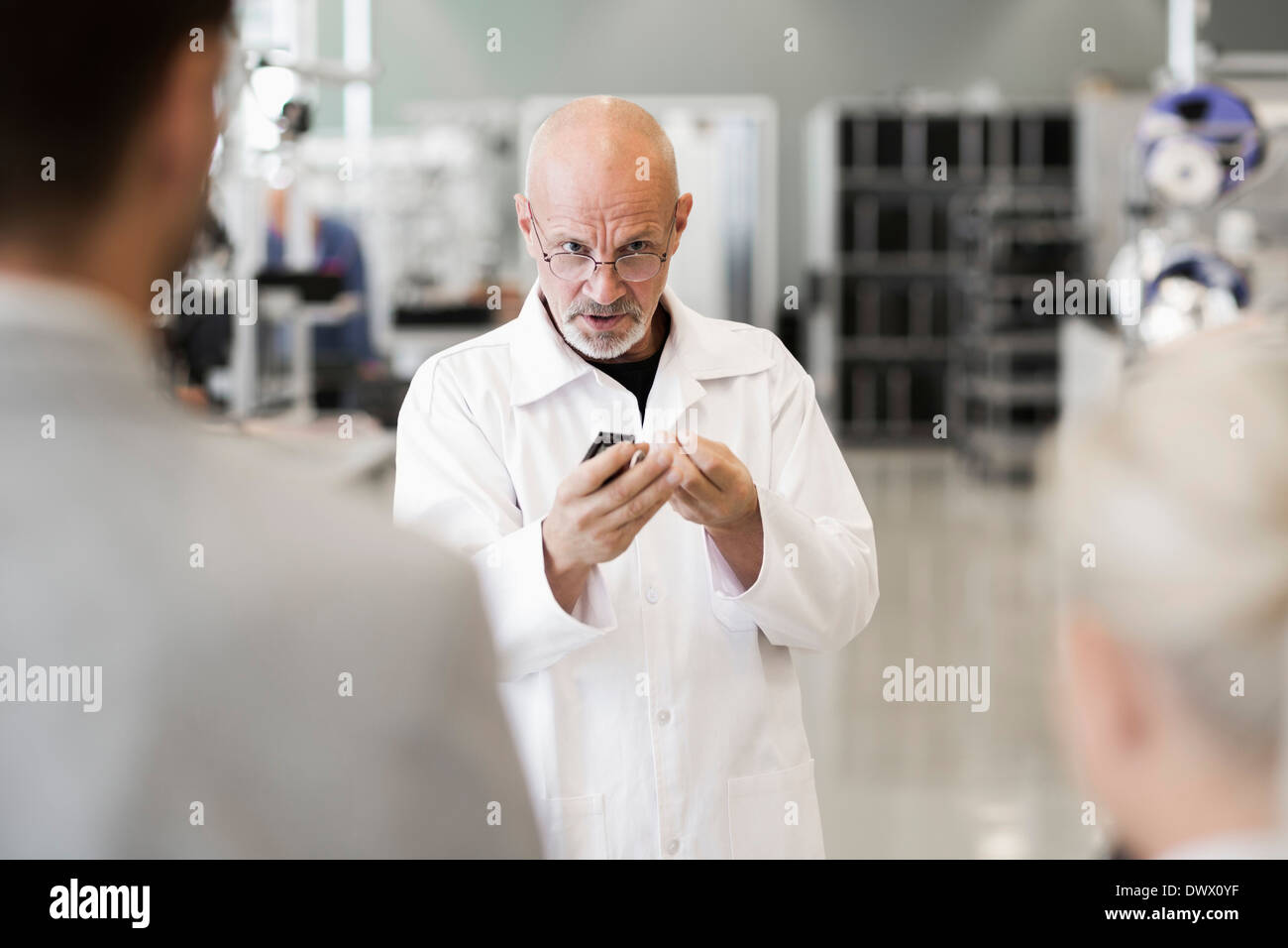 Engineer explaining machine to business people in manufacturing plant ...
