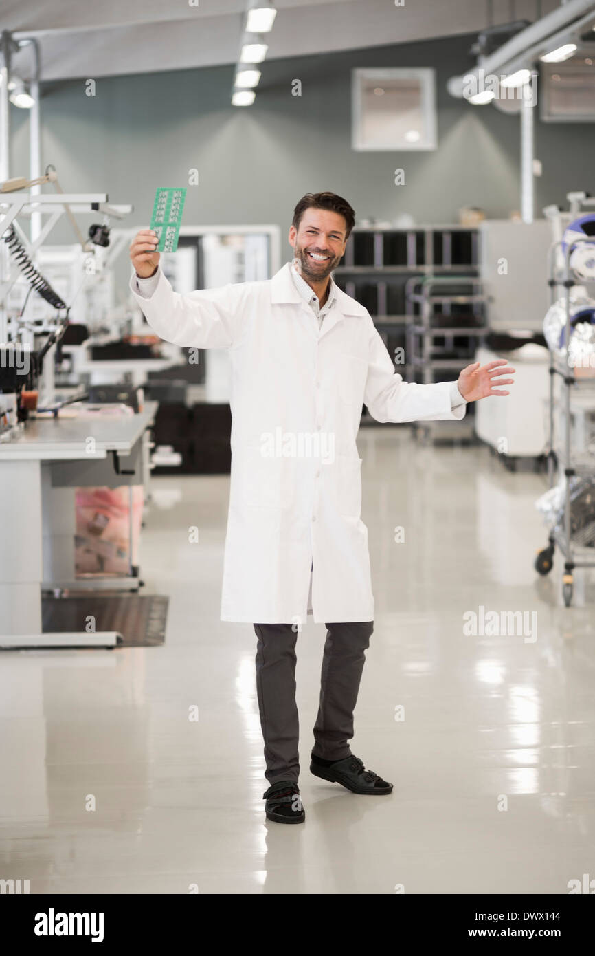 Full length portrait of happy engineer showing machine part in ...