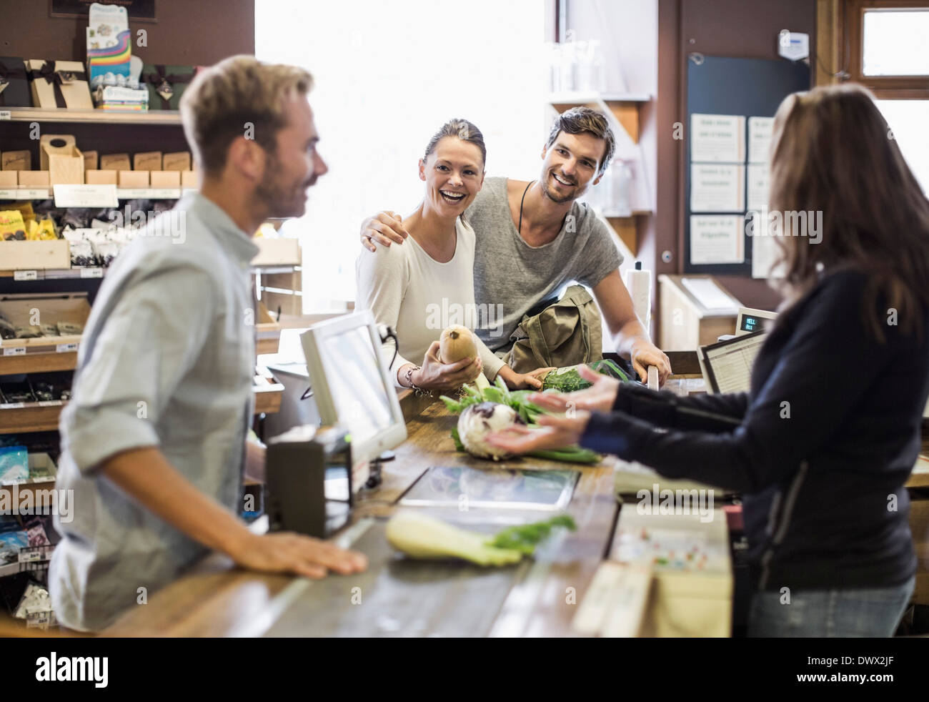 Happy friends with cashier at checkout counter in supermarket Stock ...
