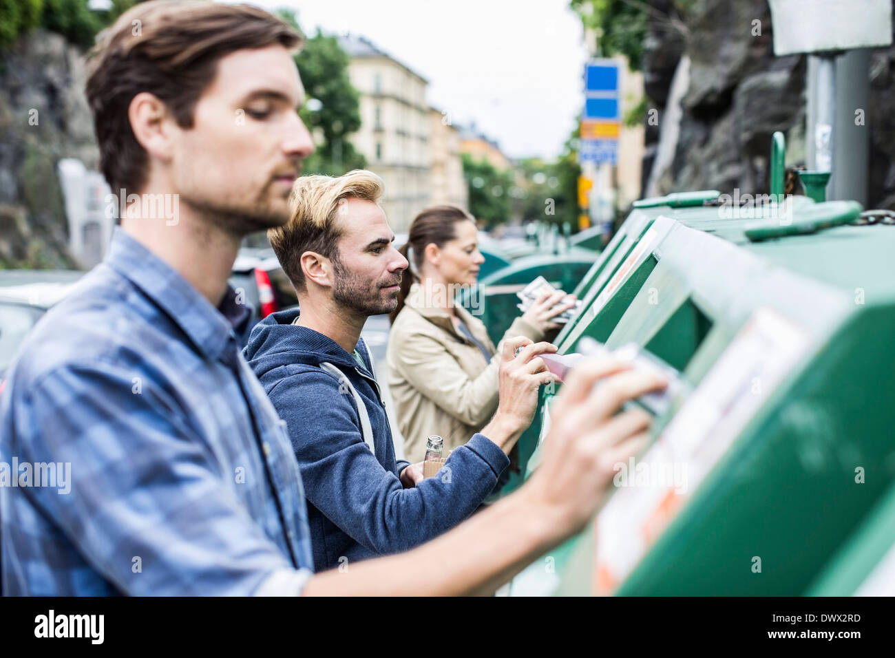 Friends putting recyclable materials into recycling bins Stock Photo ...