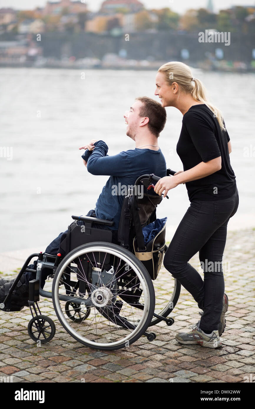 Happy disabled man with caretaker enjoying view by lake Stock Photo - Alamy