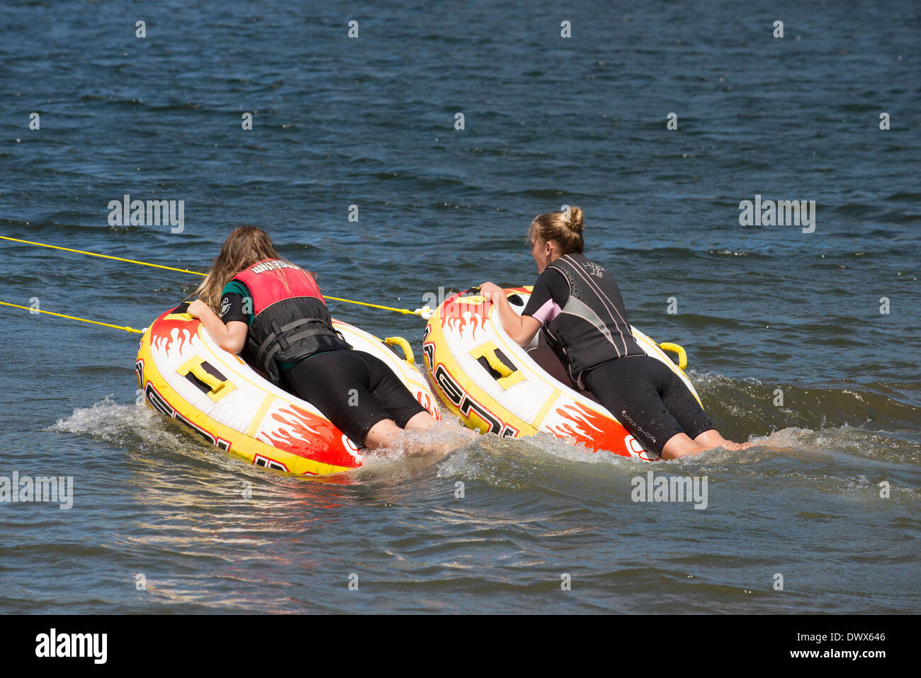 Two Teenage Girls Ride Inflatable Donut Being Pulled By A Speedboat On