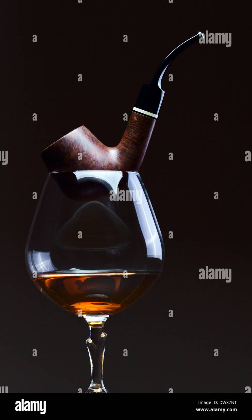 pipe and snifter with brandy on dark background Stock Photo - Alamy
